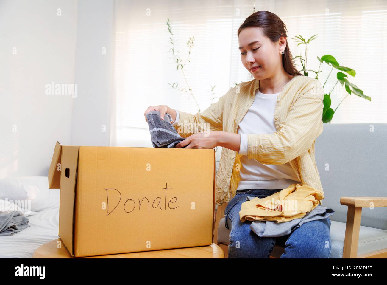 volunteer asian woman putting unused clothes into cardboard boxes for ...
