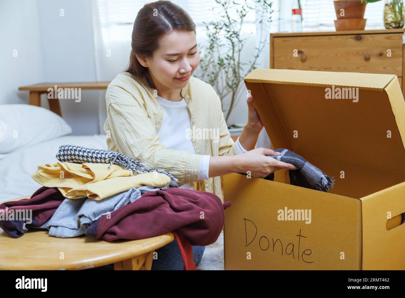 volunteer asian woman putting unused clothes into cardboard boxes for ...