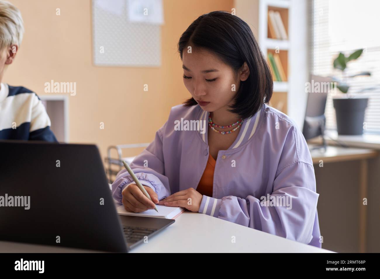 Young student of highschool looking through her notes in copybook while ...