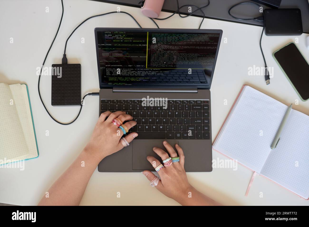 Above view of female student hands with rings on fingers typing on laptop keyboard while sitting ...
