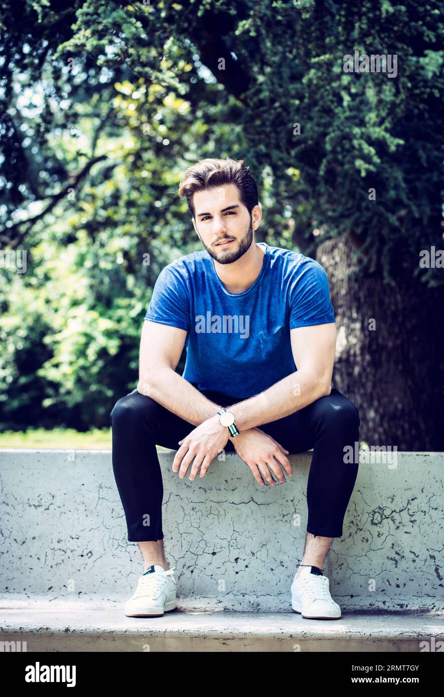 Photo of a man sitting on a cement bench in front of a tree Stock Photo ...
