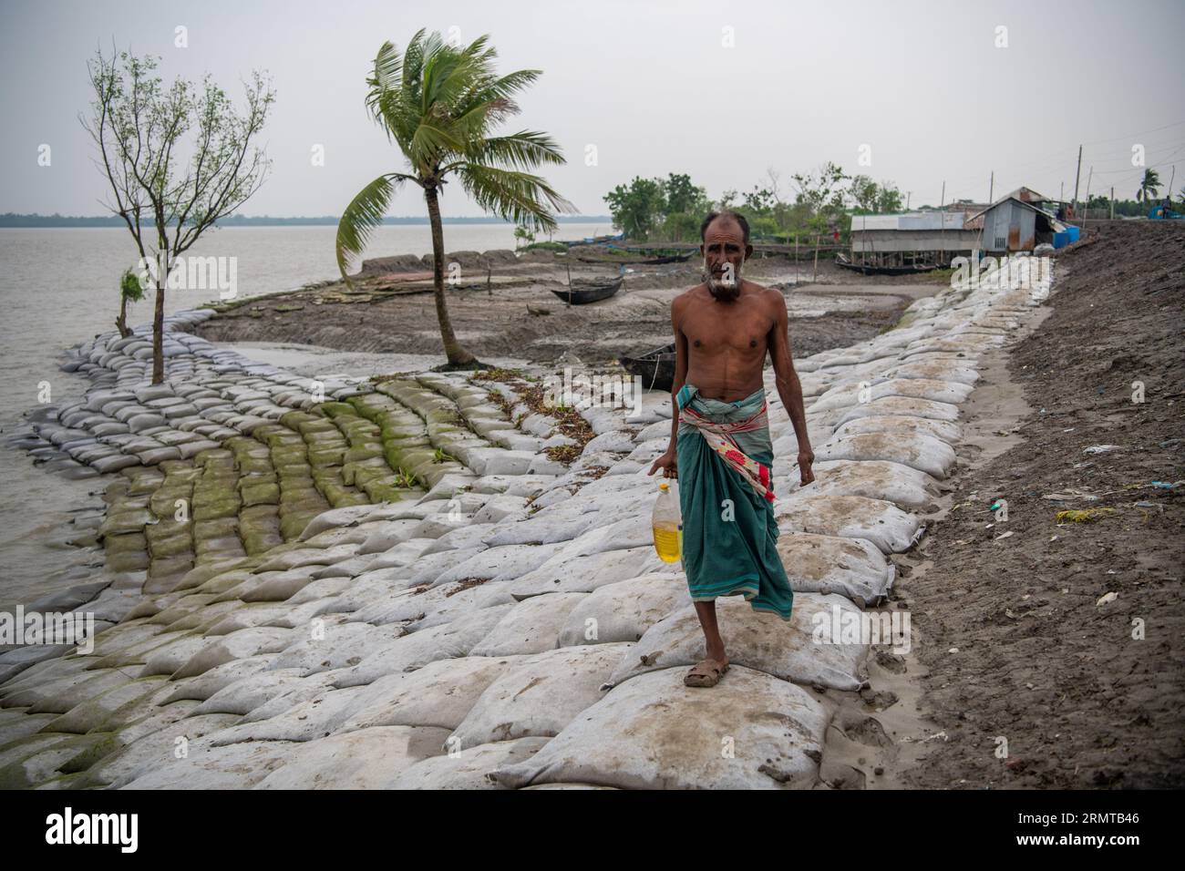A man walks along a muddy area near the damaged river dam after heavy ...