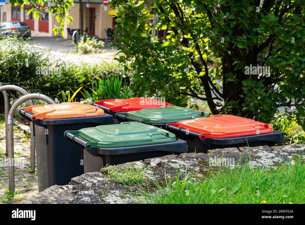 Garbage cans with multi-colored plastic lids stand in an area with ...