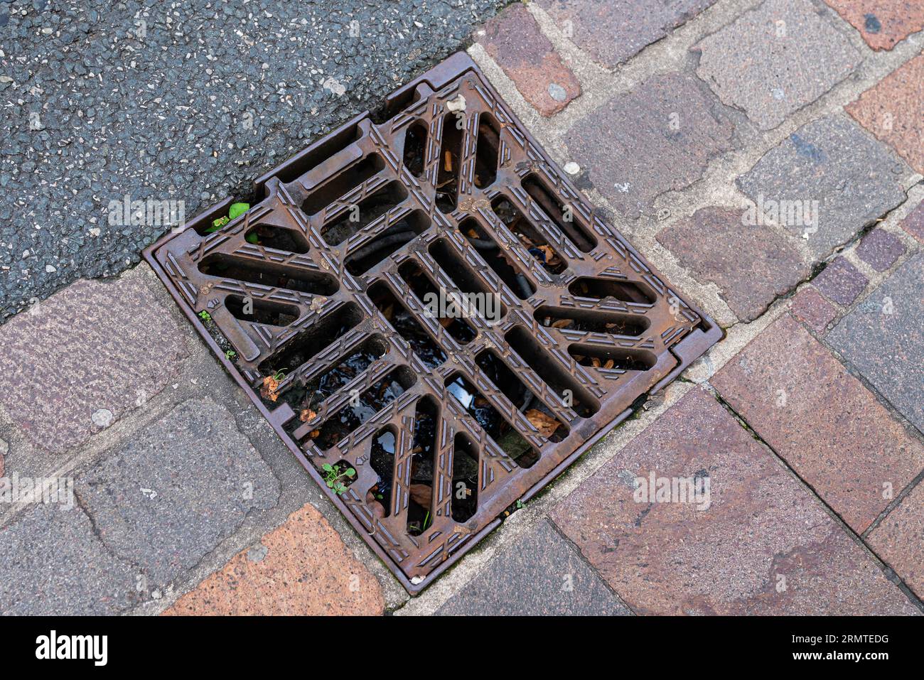 Cast-iron sewer grate on the sidewalk. Close up Stock Photo - Alamy