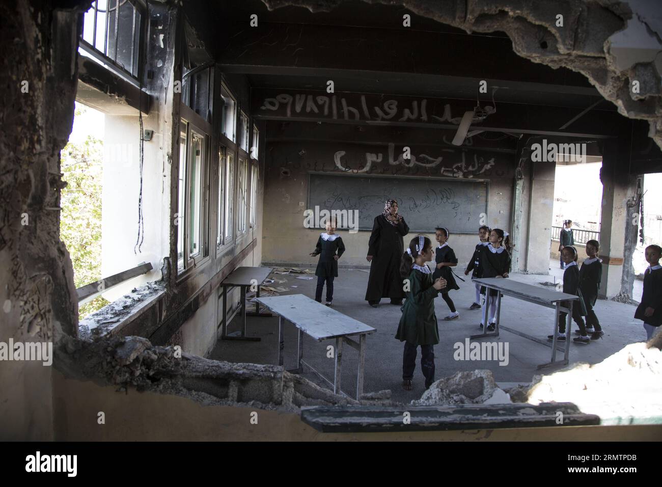 Palestinian students study inside their damaged classroom on the first ...