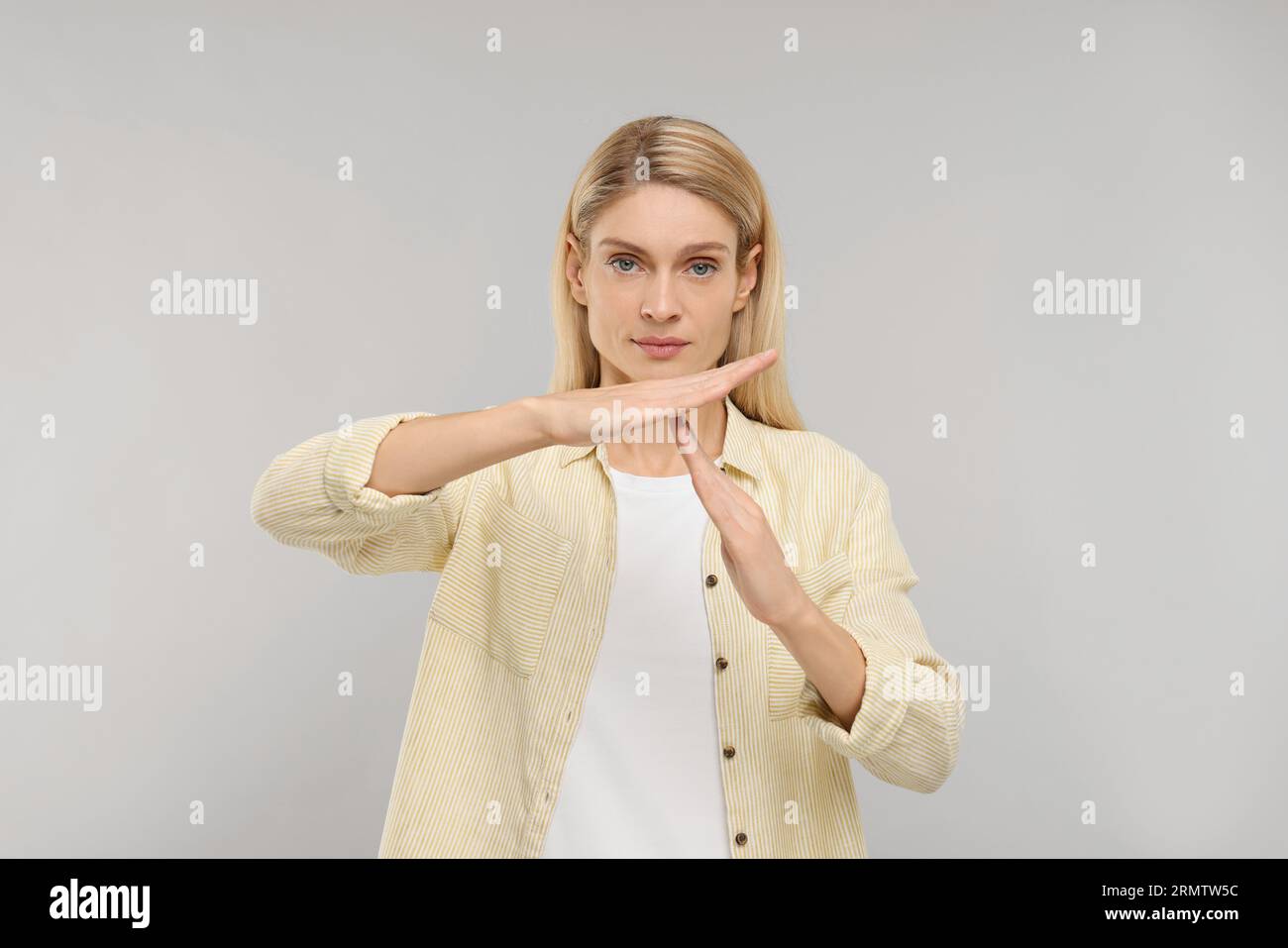Woman showing time out gesture on grey background. Stop signal Stock ...