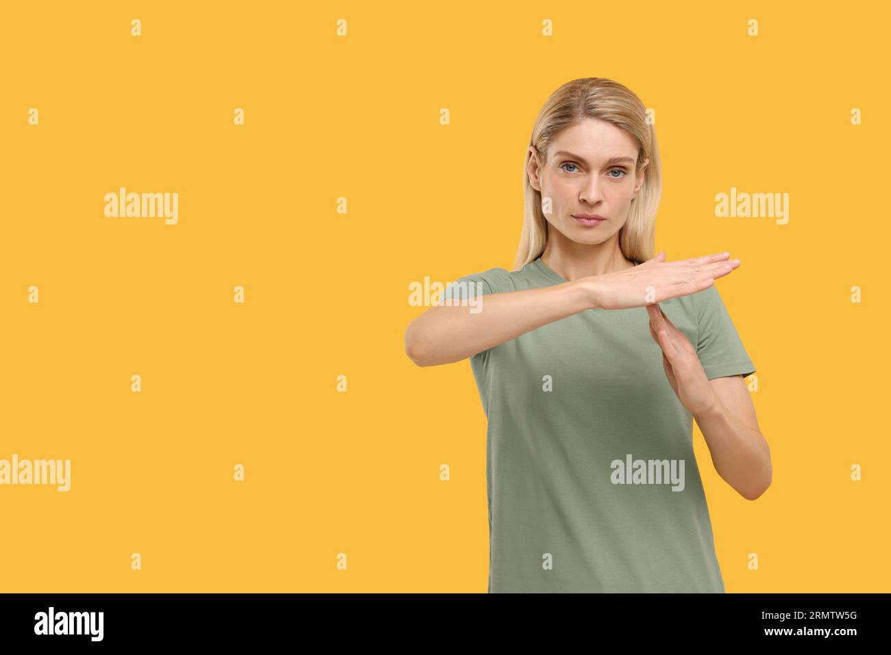 Woman showing time out gesture on yellow background, space for text ...