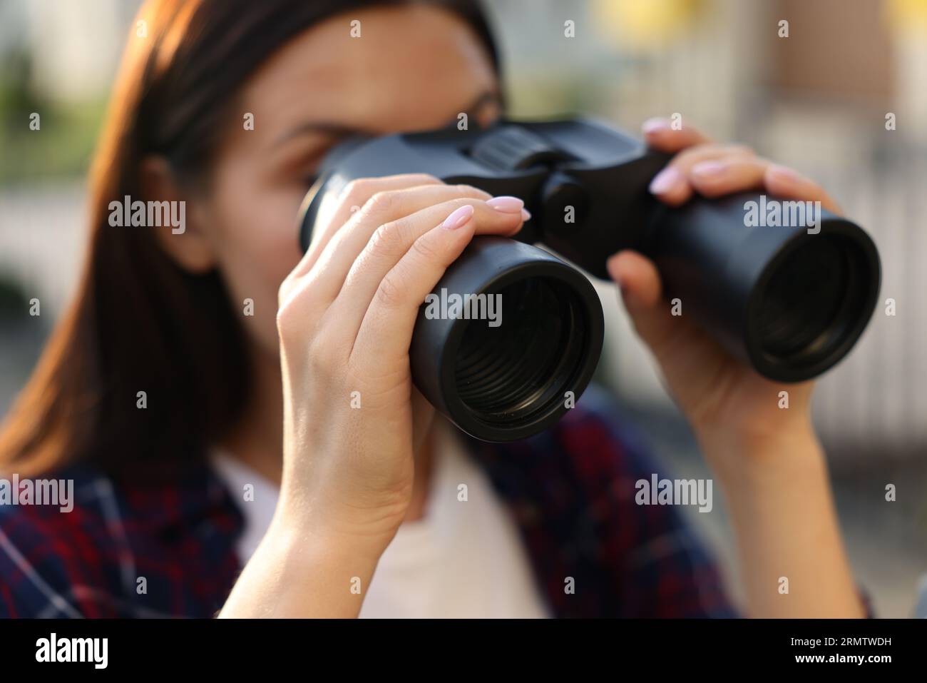 Concept of private life. Curious young woman with binoculars spying on ...