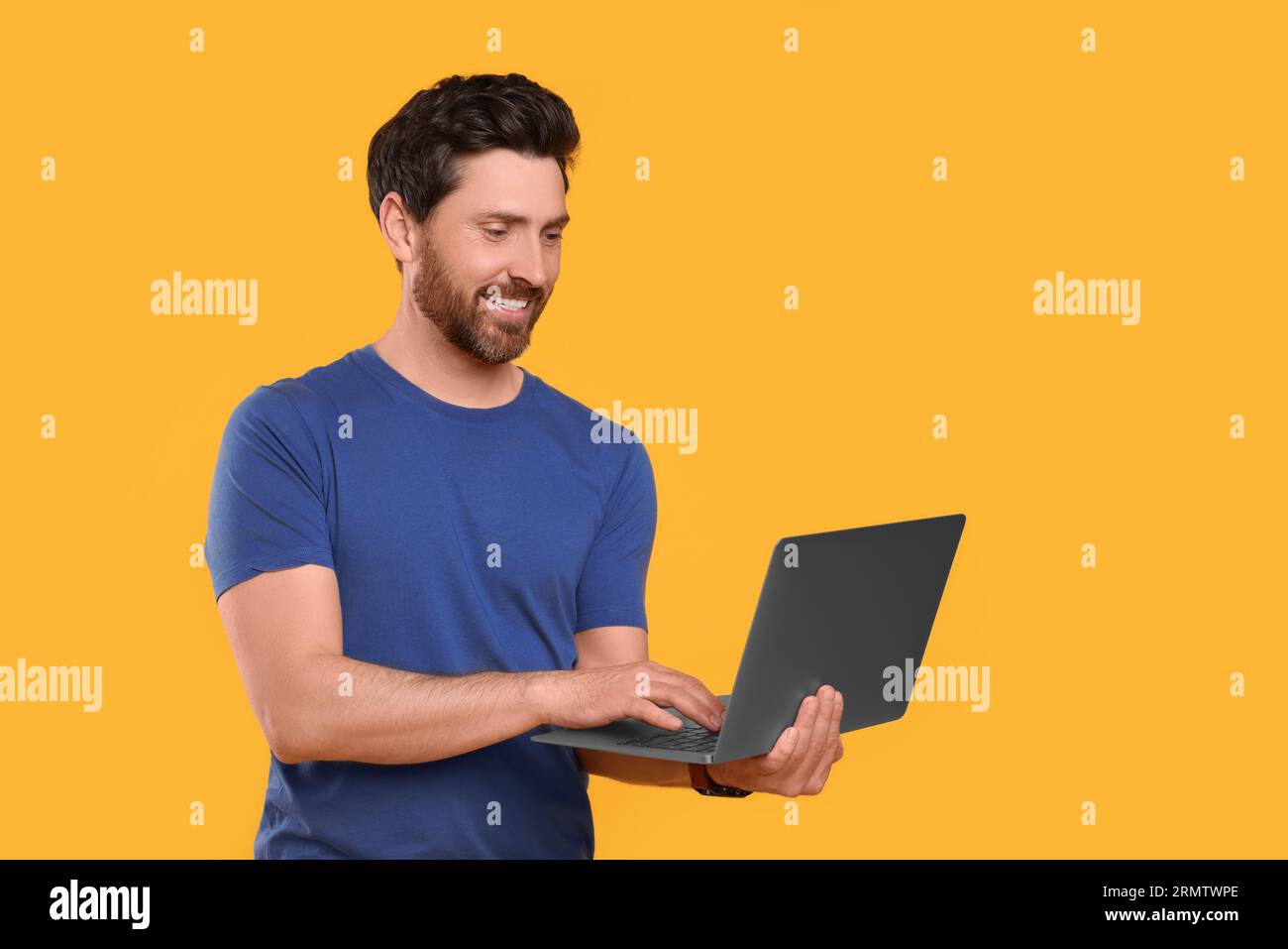 Happy man with laptop on yellow background Stock Photo - Alamy