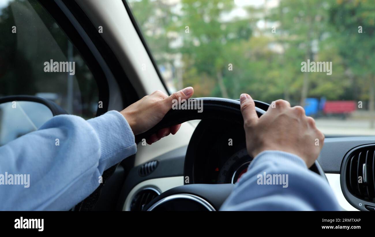 Close up of female hands spinning steering wheel driving a car ...