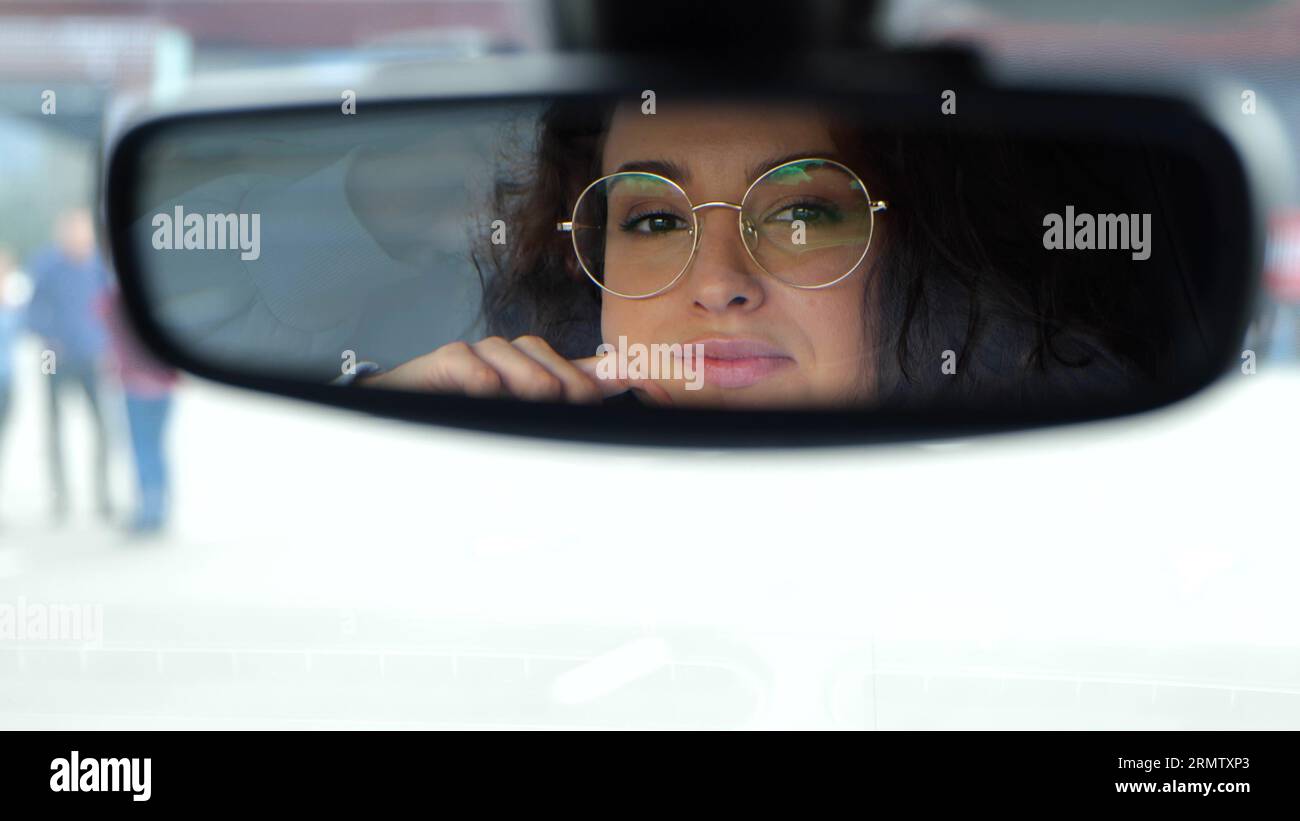 Happy female driving a car. Close up of pretty woman face in rearview ...