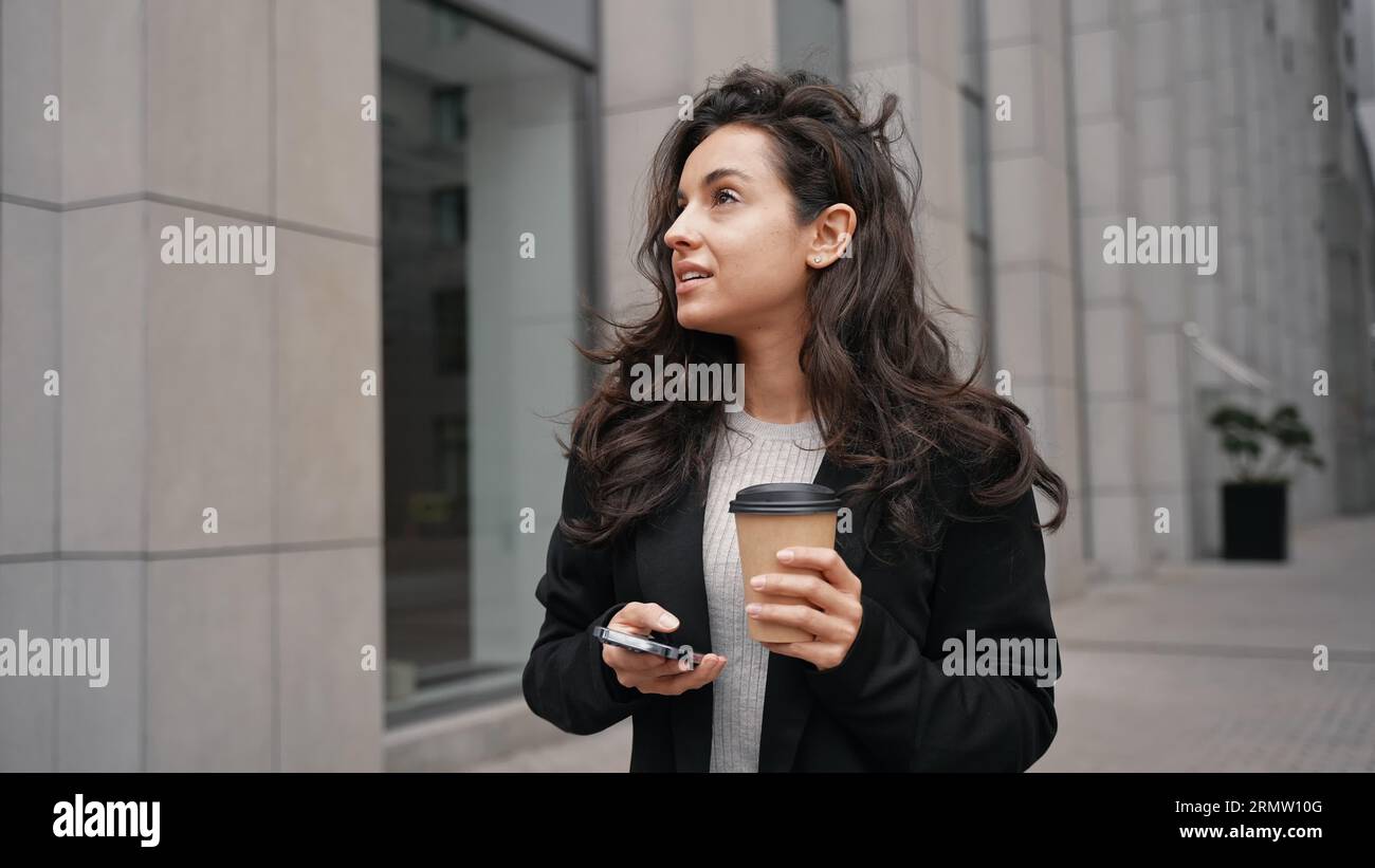 Female with dark long hair walking in city center, a girl is smiling ...
