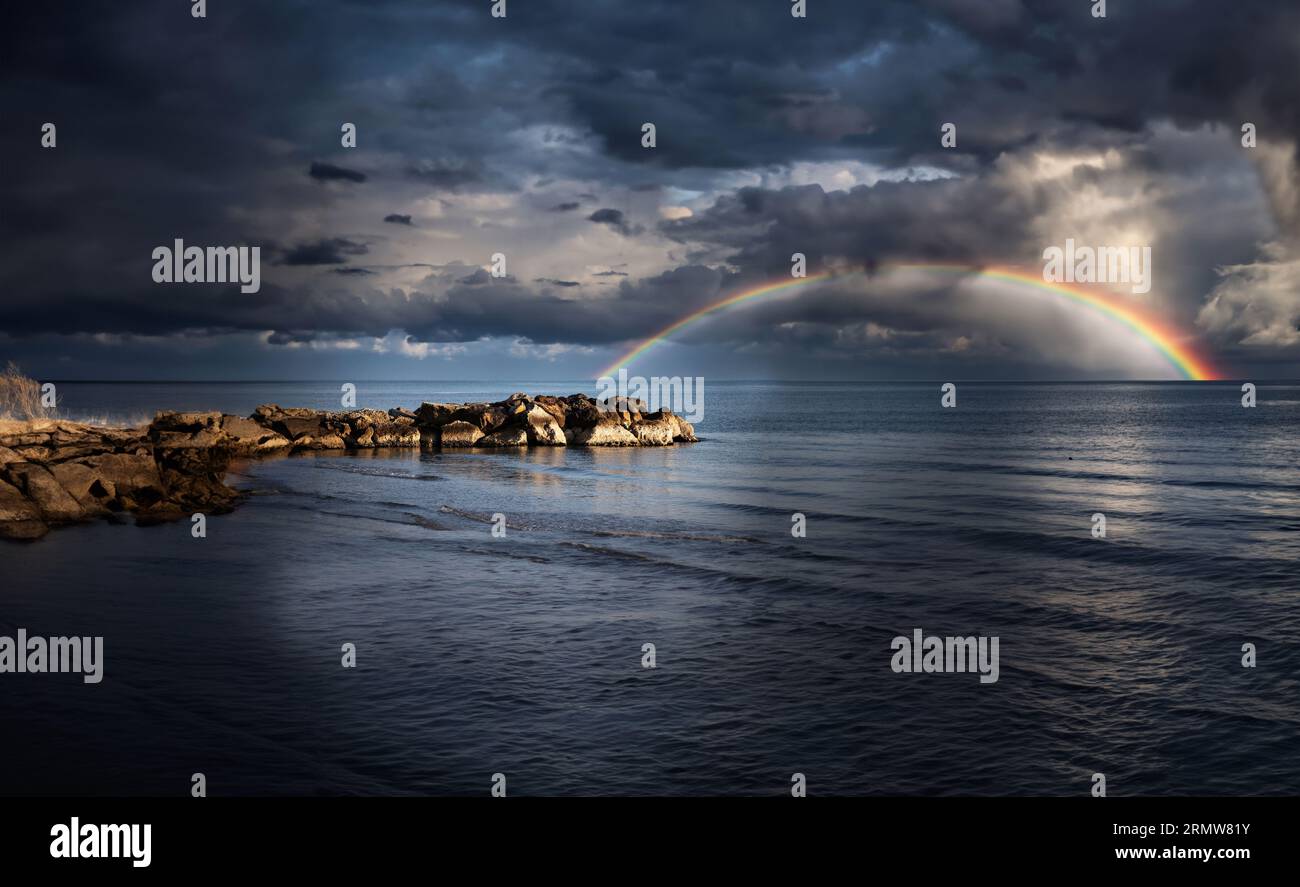 seascape rocks illuminated by the sunset with rainbow over the sea ...
