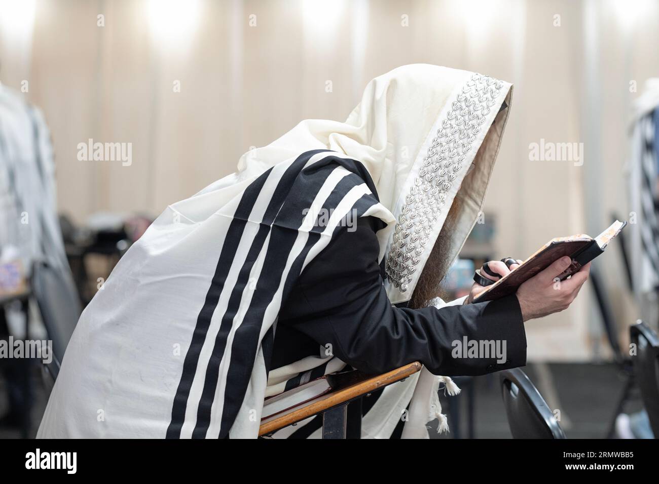 An orthodox Jewish man wearing a tallis prayer shawl recites morning ...