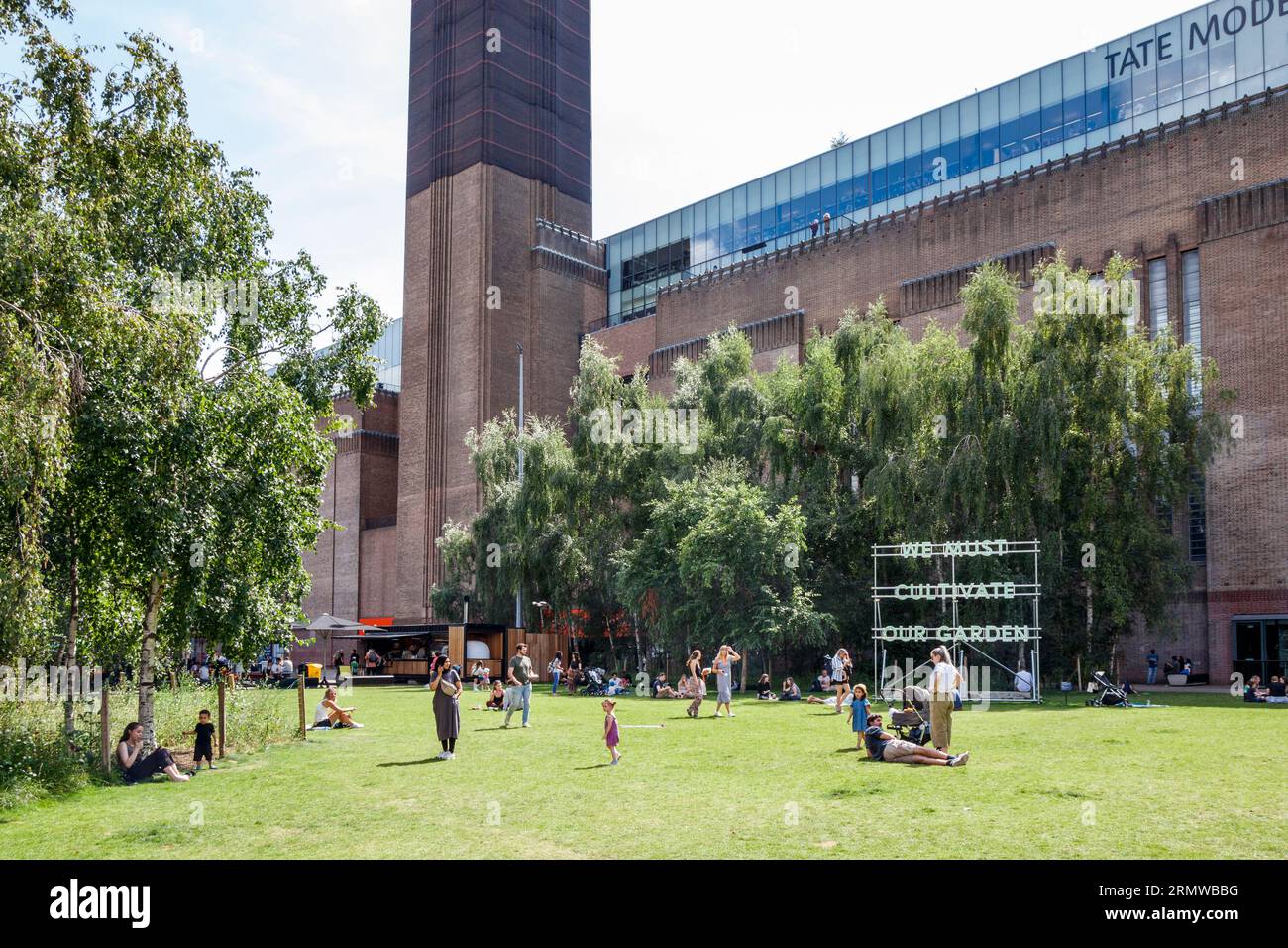 People enjoying the sunshine on the grass outside the Tate modern art ...