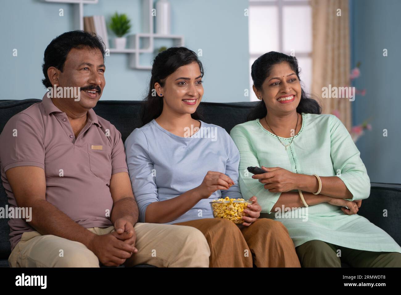 Relaxed Happy indian parents with daughter watching tv or television by ...