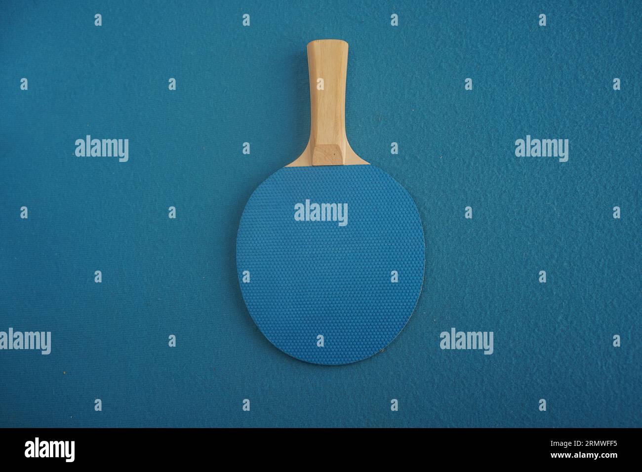 Blue table tennis or ping pong racket lies upside down on blue ...