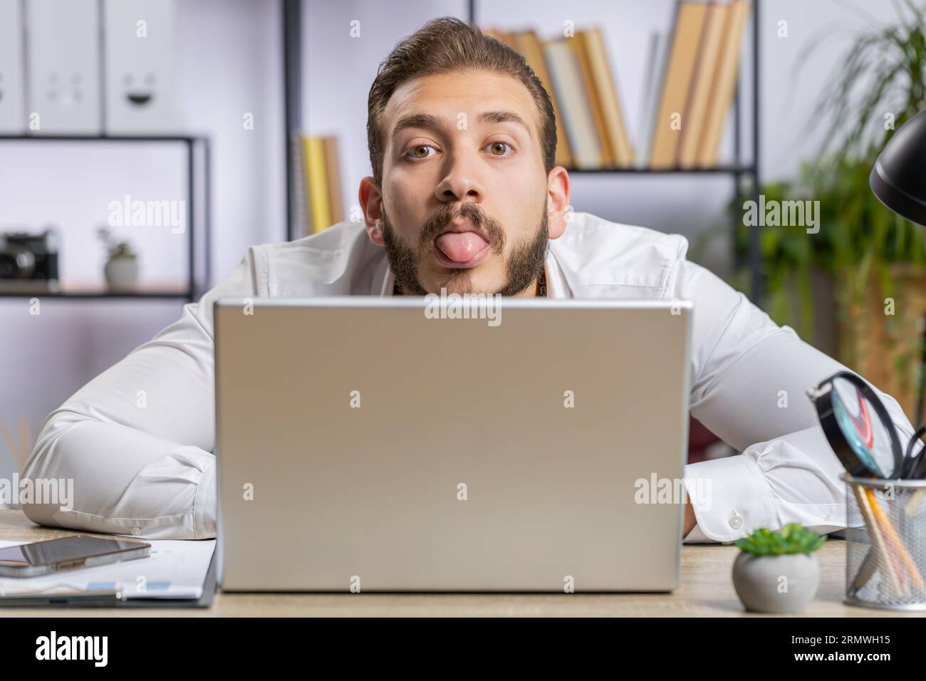 Lebanese businessman hiding behind laptop computer, making funny face ...