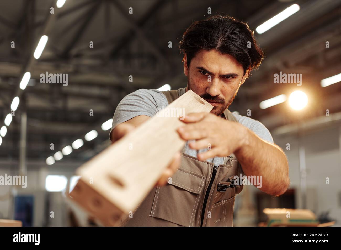 Young carpenter man looking and choosing wood plank at workshop in ...