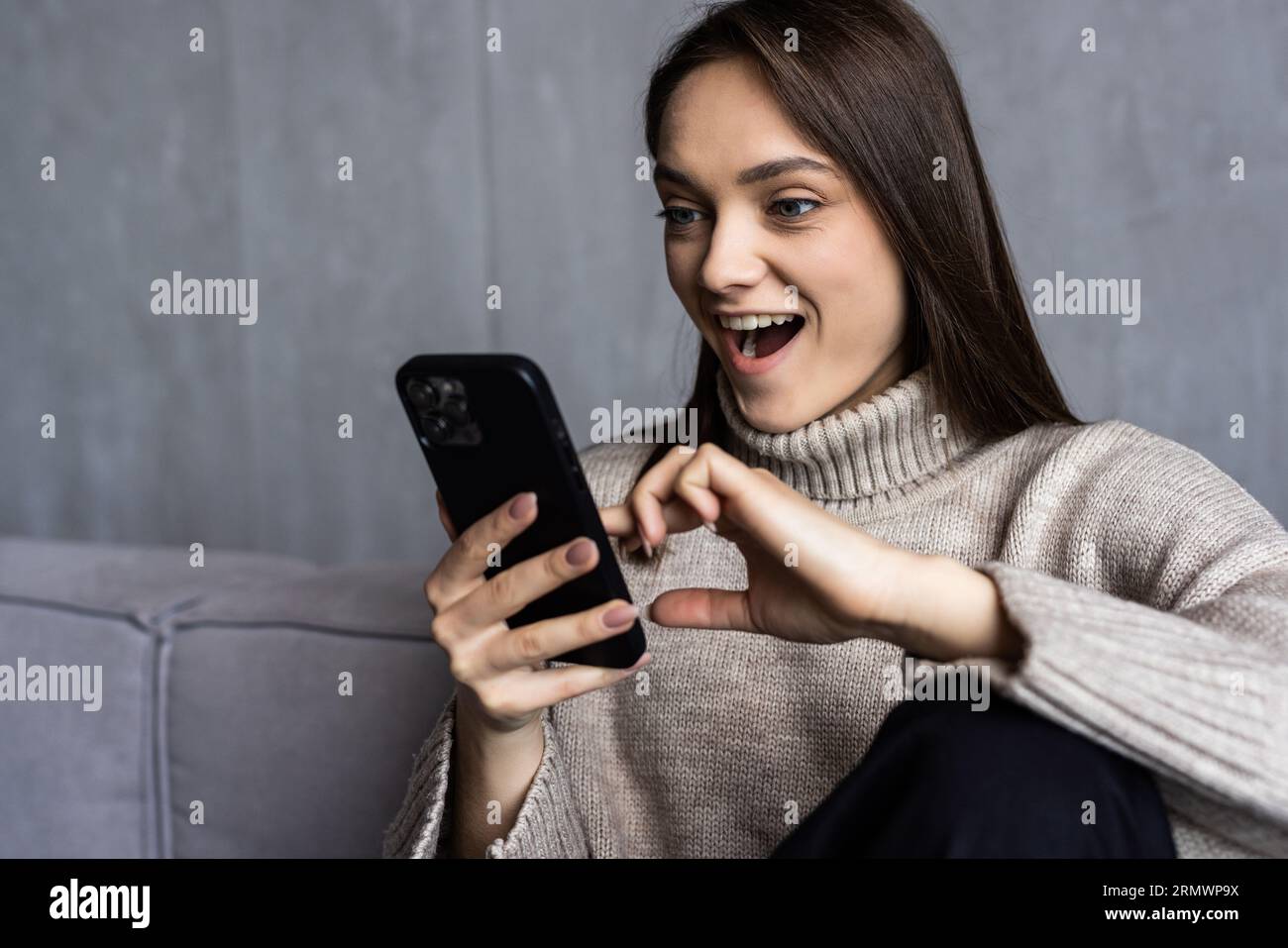 Surprised woman with open mouth looking at phone screen, reading ...
