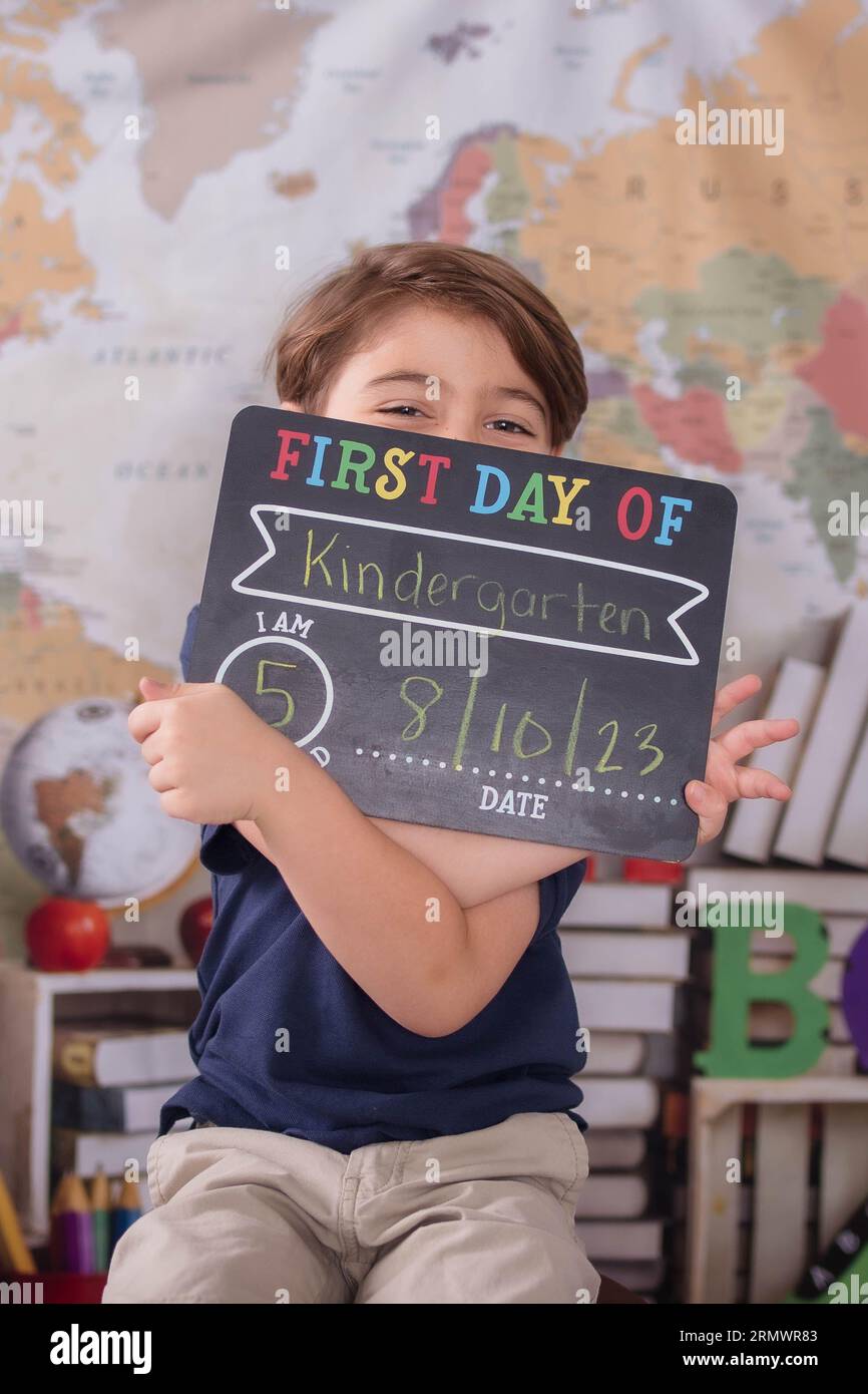 A cheerful adolescent boy holding a chalkboard sign for the first day ...