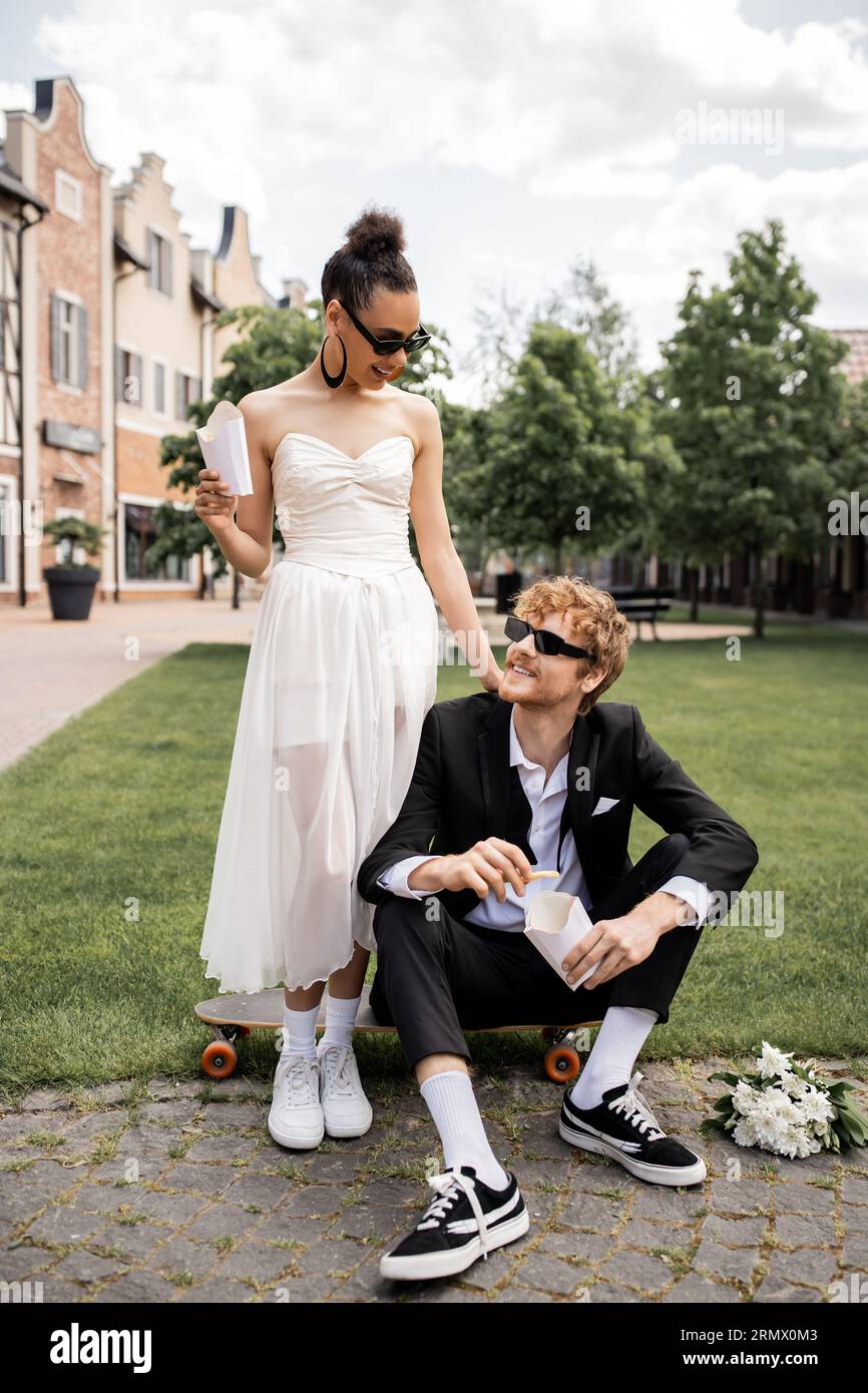 elegant african american bride near groom sitting on longboard on ...