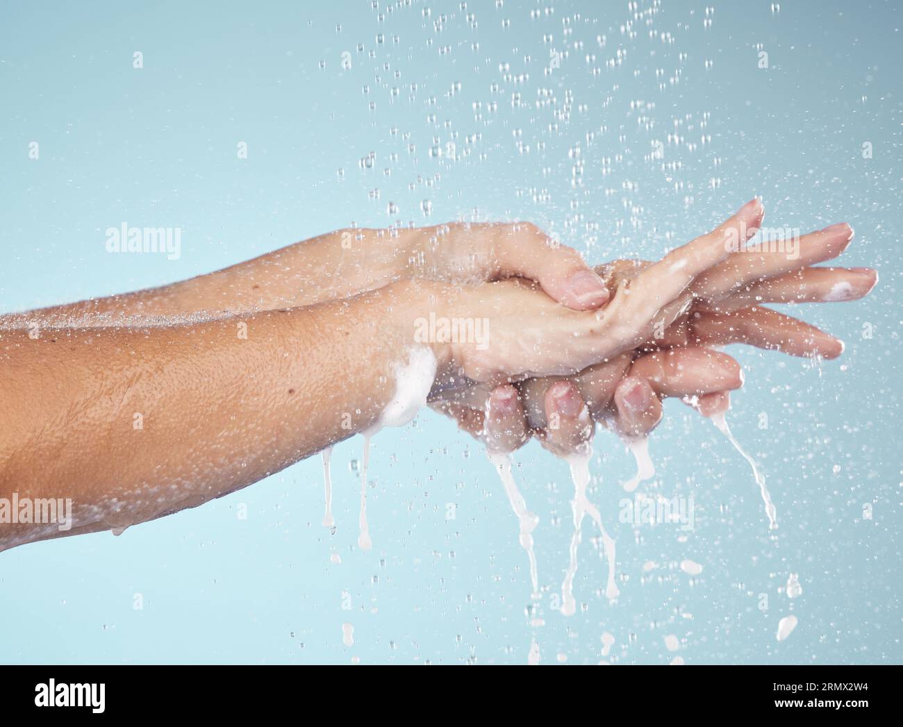 Woman, cleaning and hands with water splash in studio, blue background ...