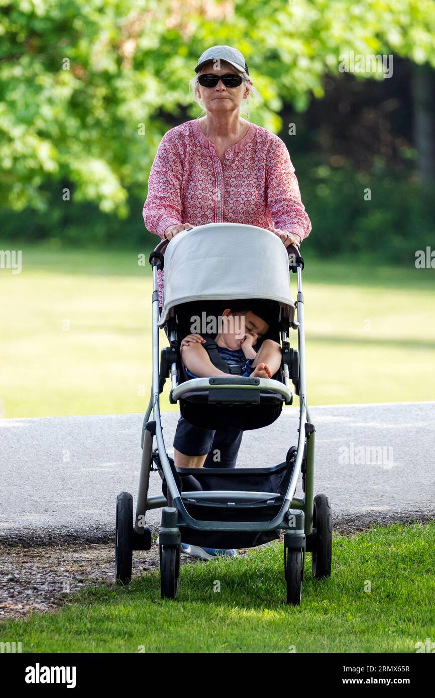 Grandmother pushing young grandson in stroller on a hot summer day ...