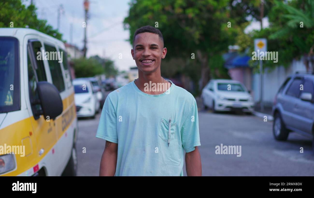 One cheerful young Brazilian man waving hello to neighbor walking in ...