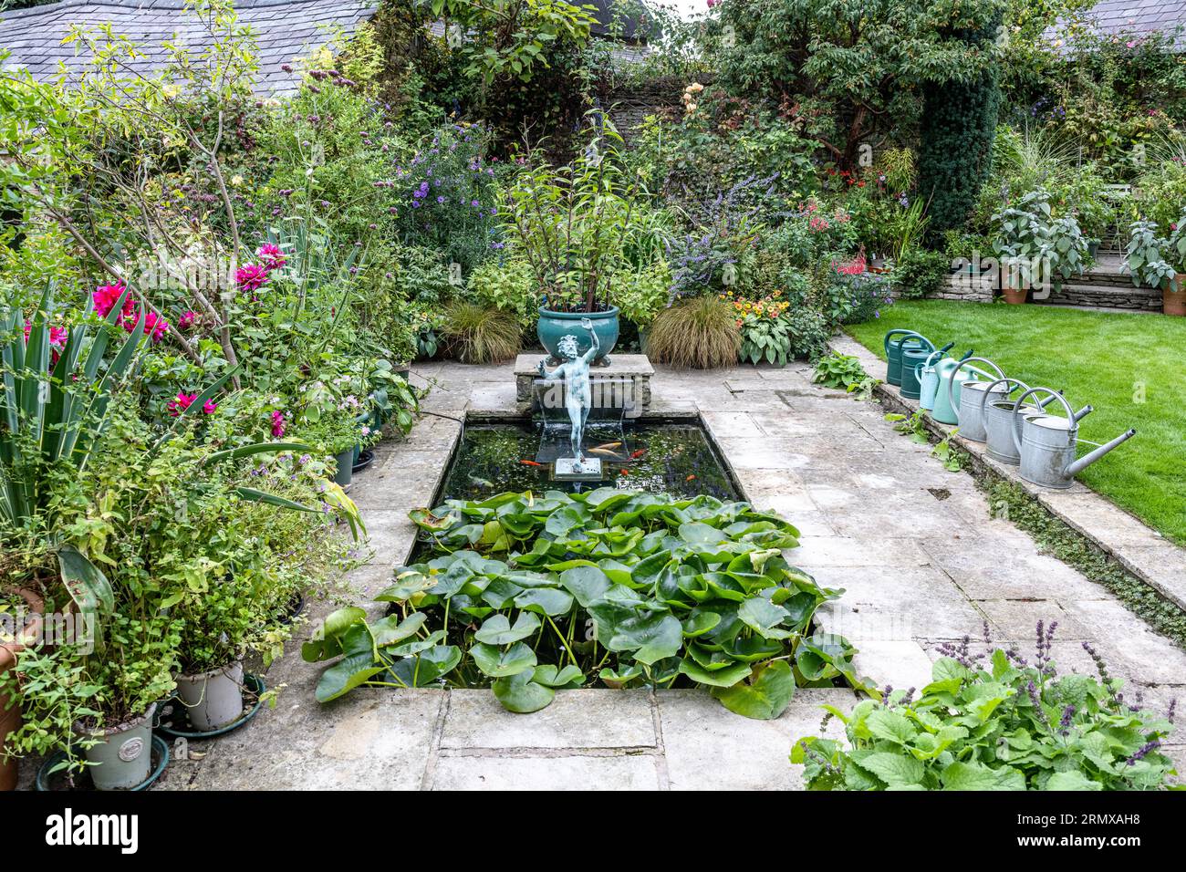 Watering cans and pond in secluded garden of 18th century Georgian ...