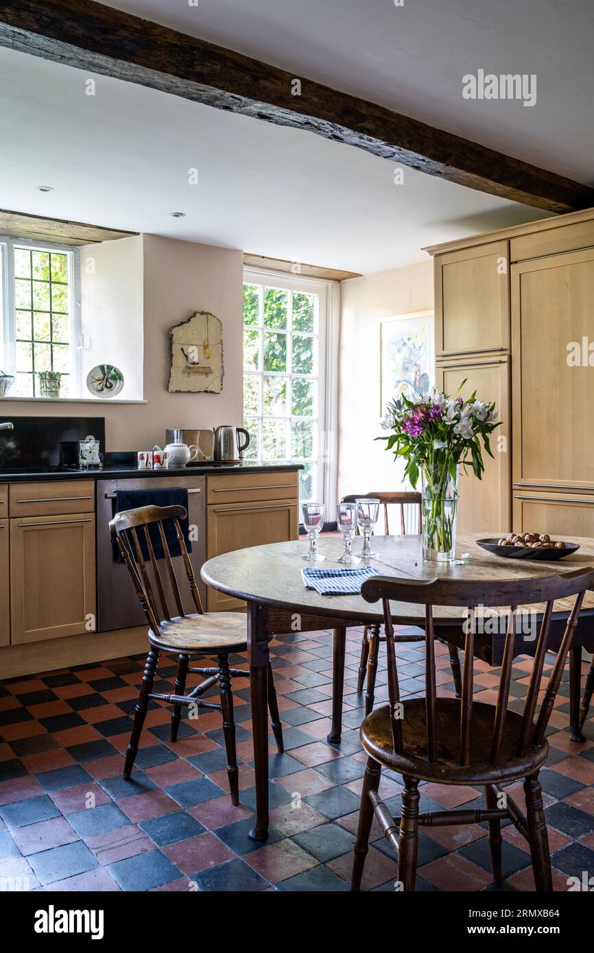 Cut flowers on wooden kitchen table with tiled floor in 18th century ...