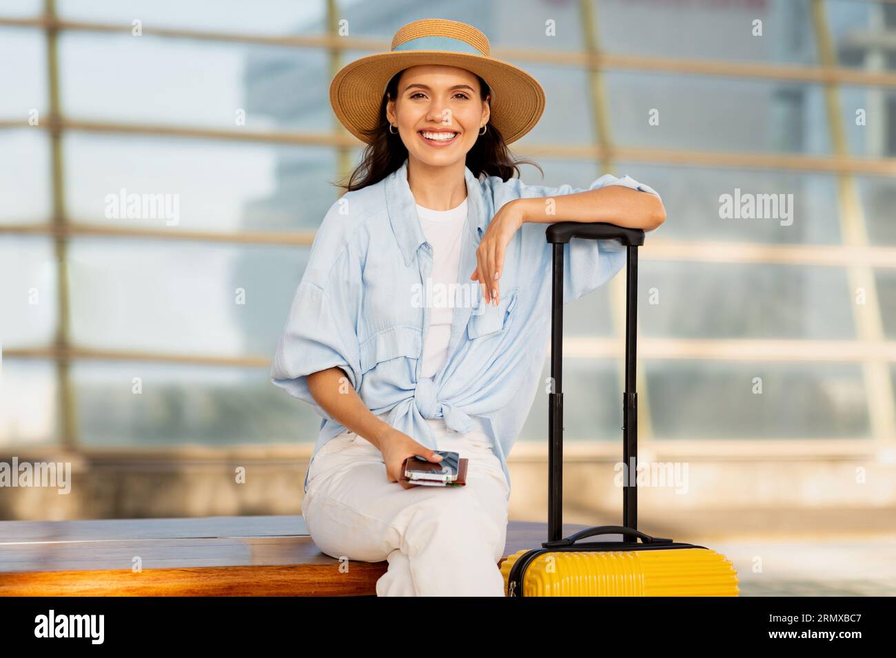 Positive young european lady tourist in hat with suitcase, uses ...