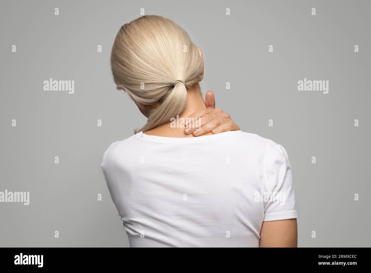 Sick mature blond woman suffering acute neck pain Stock Photo - Alamy