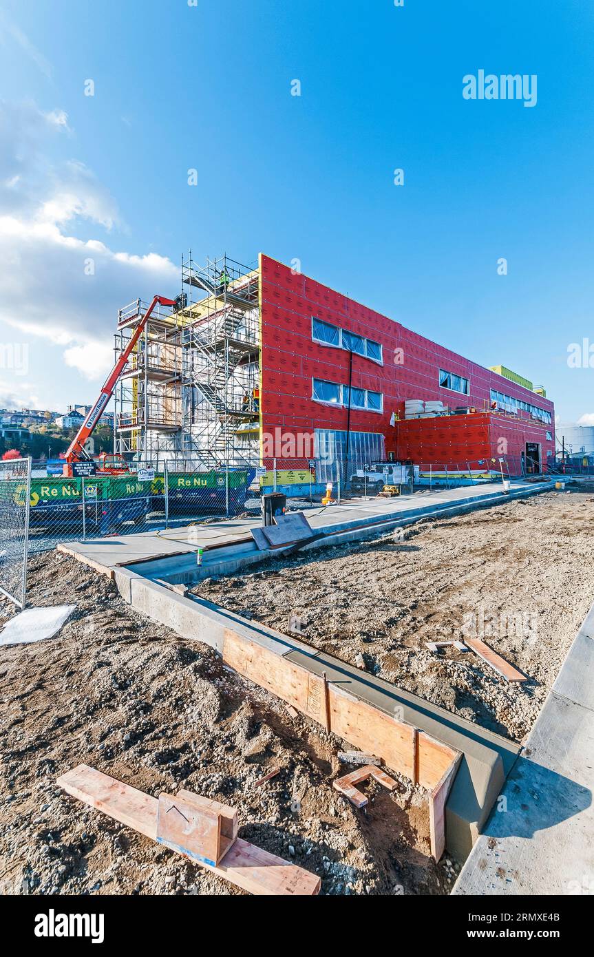 An orange rental high-lift with its arm extended to roof of building at ...