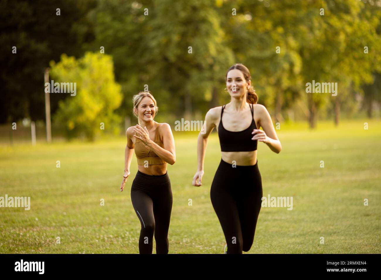 Two pretty young women running in the park Stock Photo - Alamy
