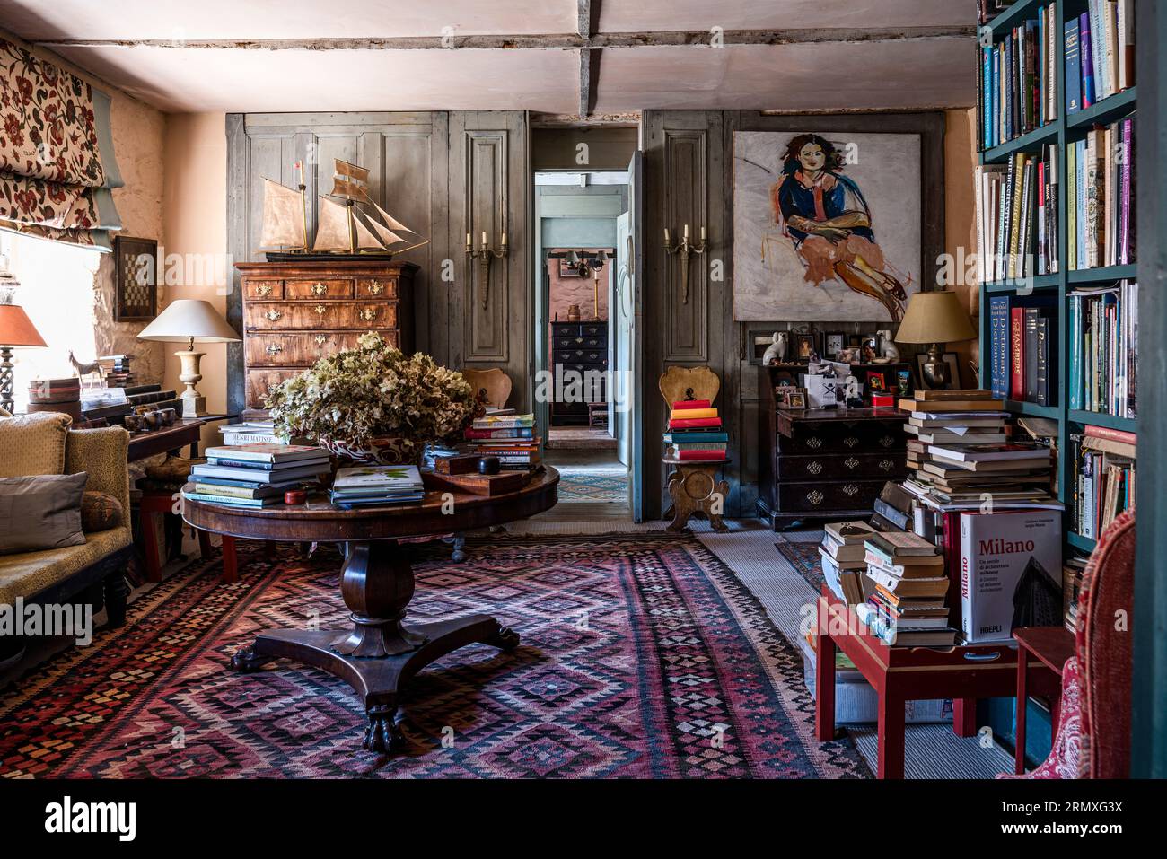 Books on pedestal base table with model of a clipper and artwork in ...