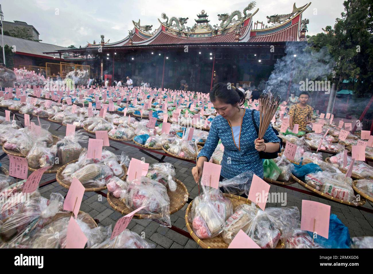 An ethnic Chinese woman arranges offerings, during the Hungry Ghost ...