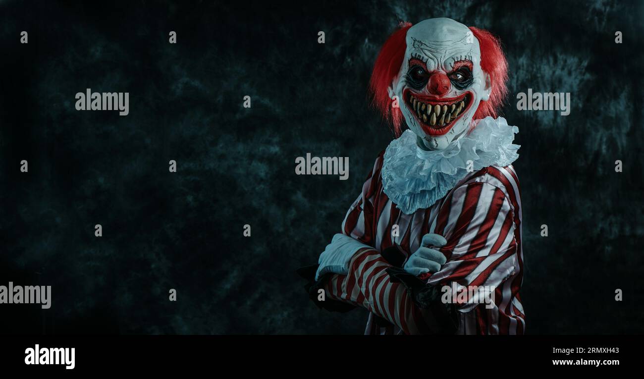 a mad evil redhead clown, wearing a white and red striped costume with ...