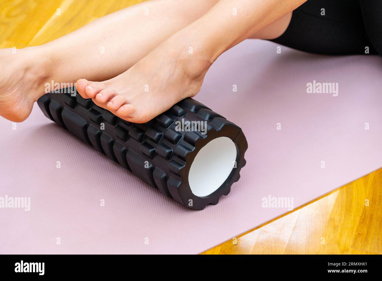 Using foam roller for self-massage of feet. Close up photo of fitness ...
