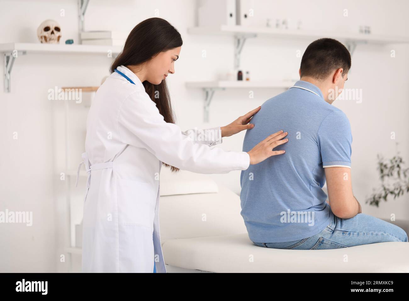 Female doctor checking posture of young man in clinic Stock Photo - Alamy