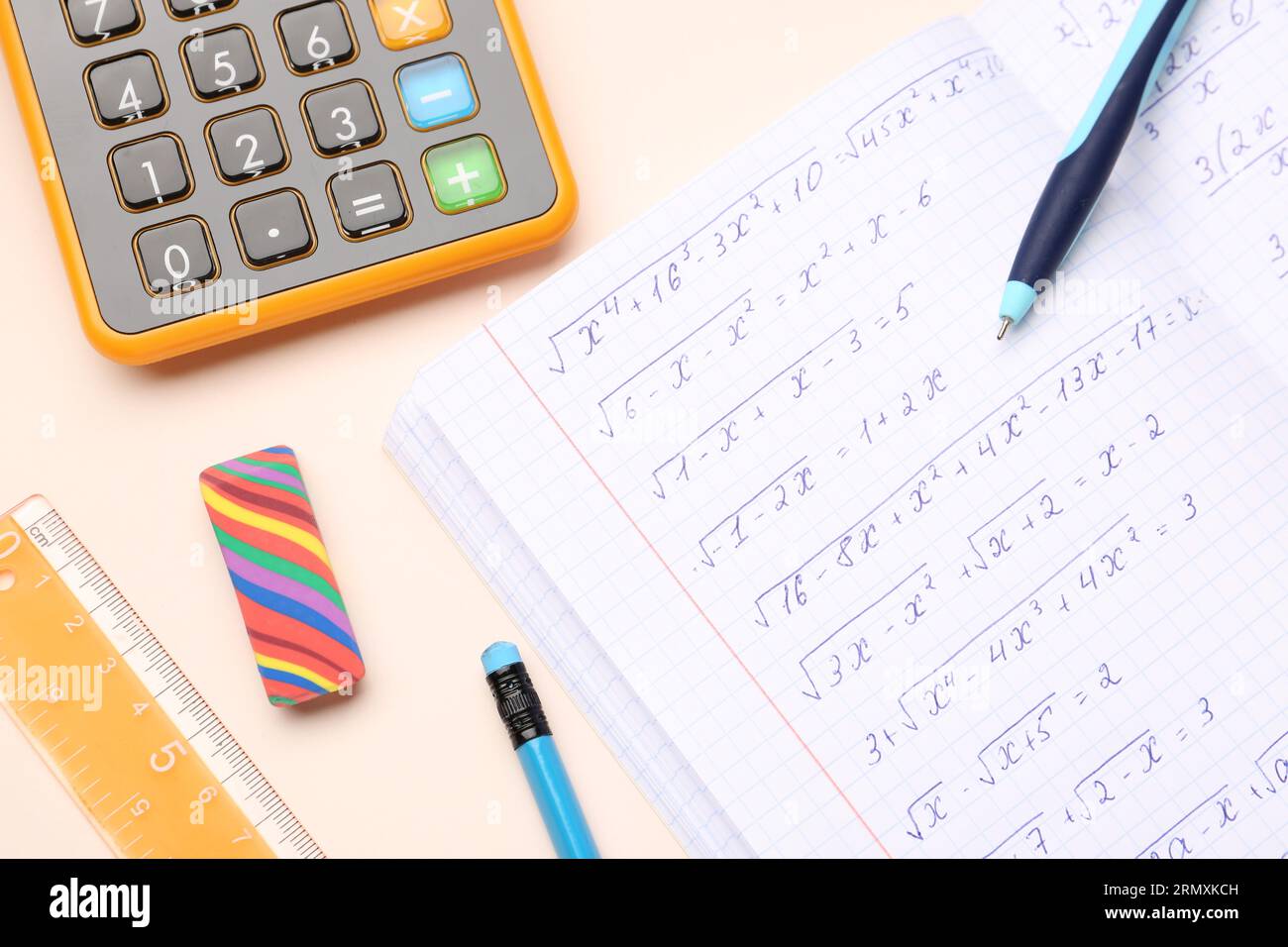 Copybook with maths formulas, calculator and stationery on beige ...