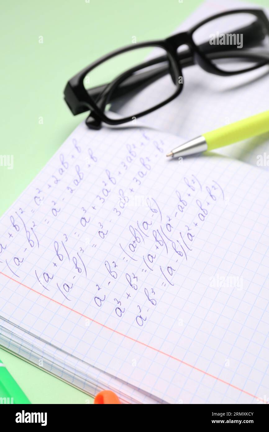 Copybook with maths formulas, glasses and pen on green background Stock ...