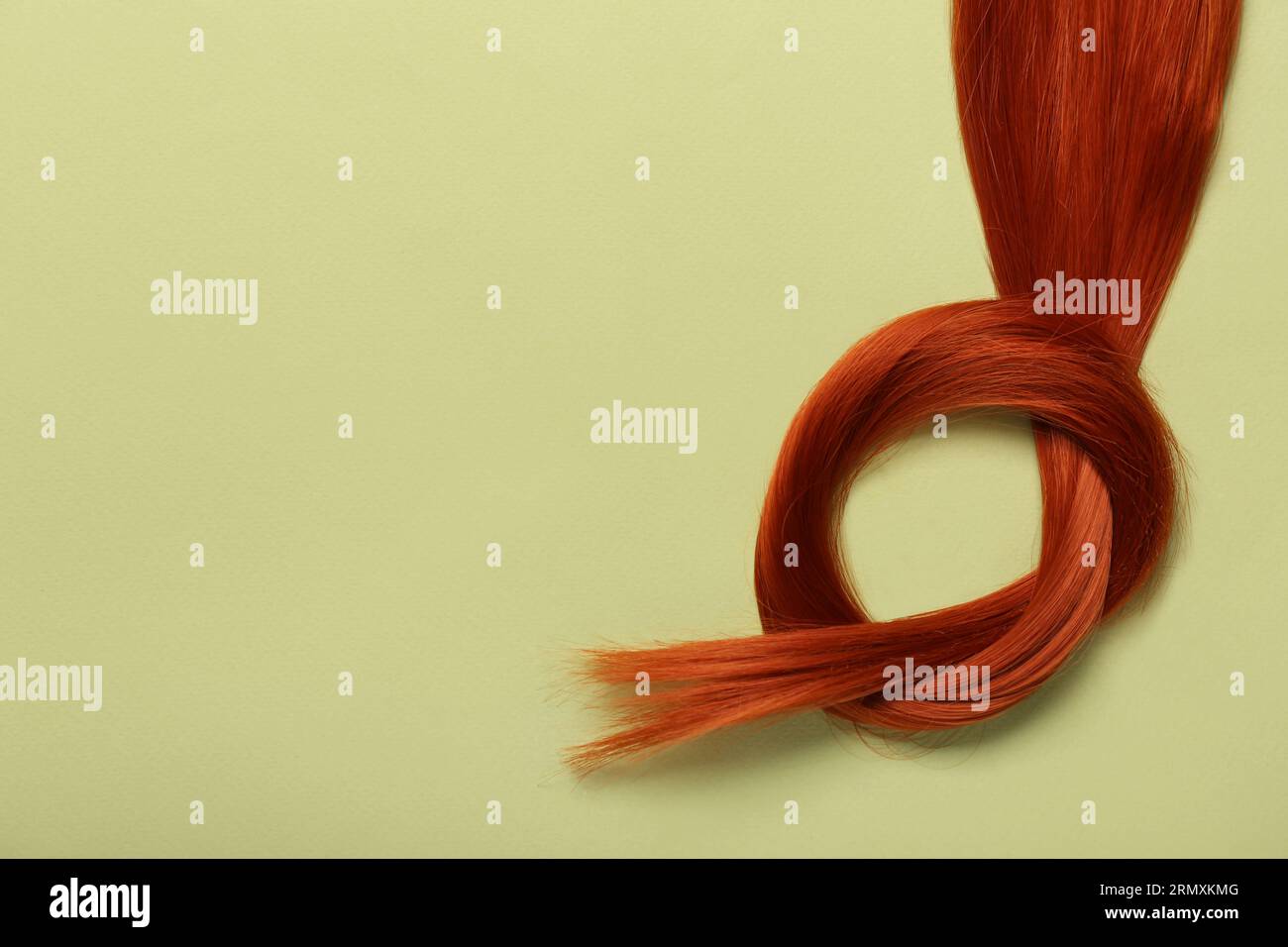 Ginger hair strand tied in knot on green background, closeup Stock ...