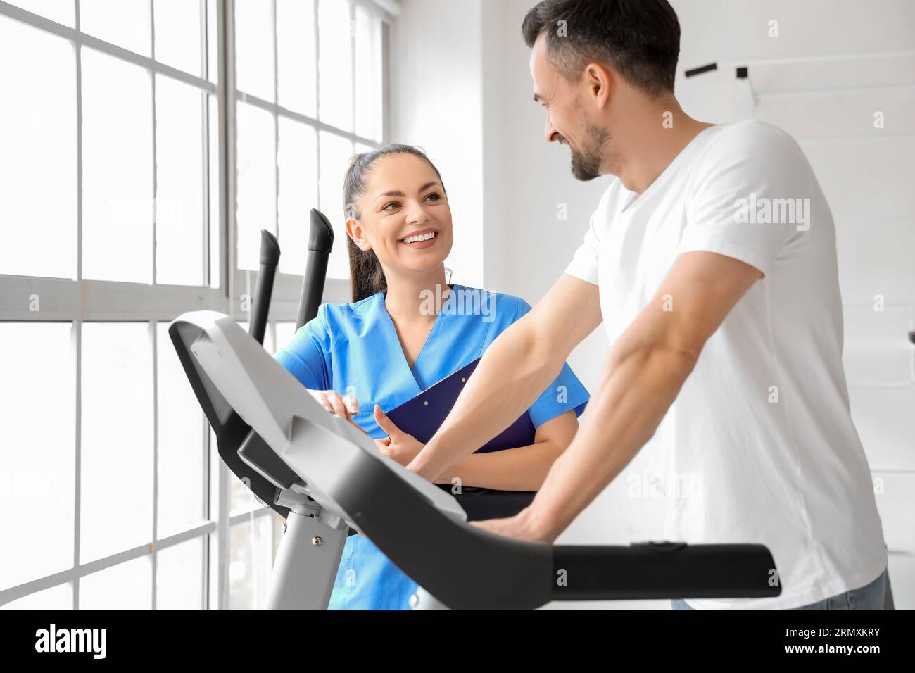 Female physiotherapist working with young man on treadmill in ...