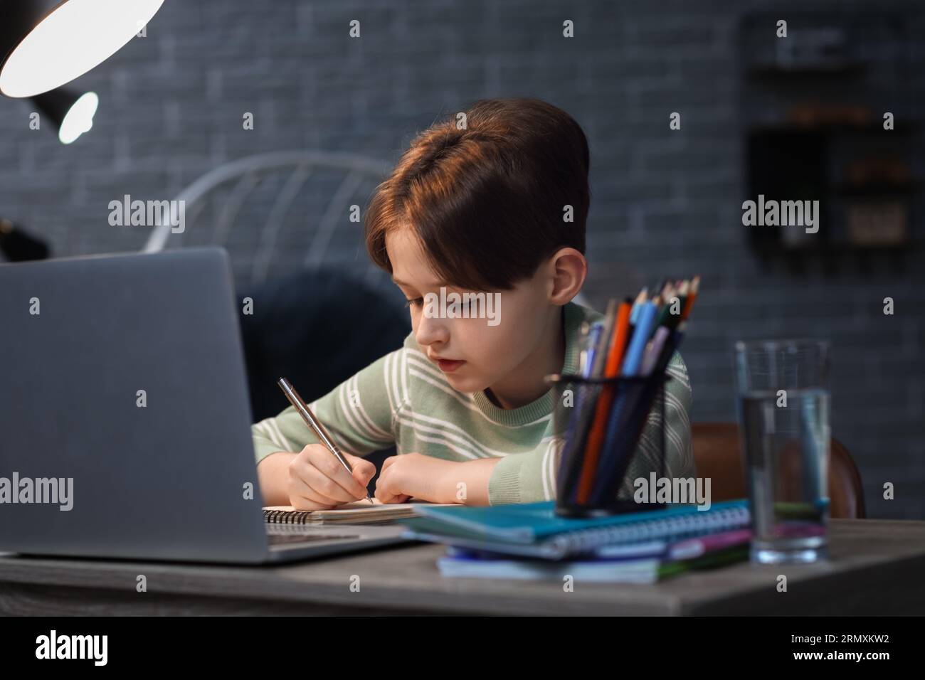 Little boy doing homework with laptop at home late in evening Stock ...