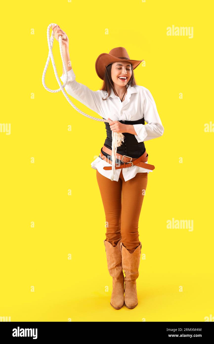 Beautiful cowgirl with lasso on yellow background Stock Photo - Alamy