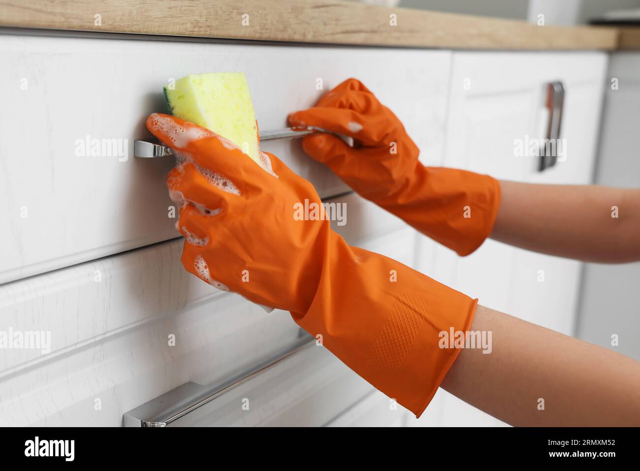 Woman in orange rubber gloves cleaning drawers of kitchen counter with ...