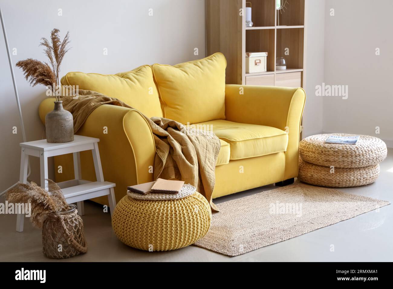 Interior of light living room with stylish yellow sofa and soft poufs ...