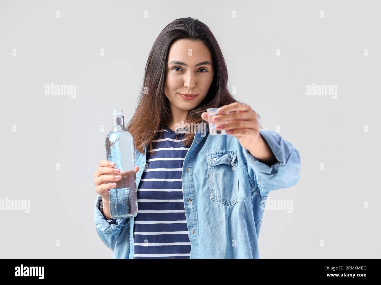 Young woman with bottle of vodka on light background Stock Photo - Alamy