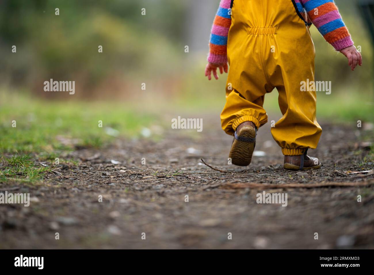 baby running down a path in yellow overalls in the bush Stock Photo - Alamy